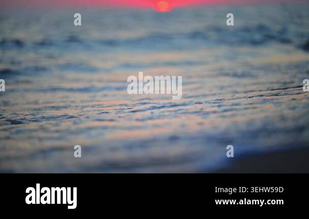 Gentle sea wave rolling onto sandy beach at colorful sunset, cinematic ...