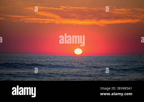 Spectacular orange sunset over calm sea with glowing sun and dramatic ...