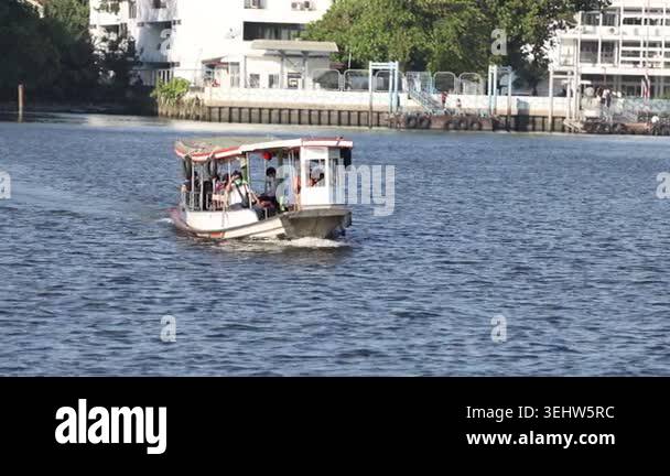 Small boat with people navigating a waterway near urban buildings and ...