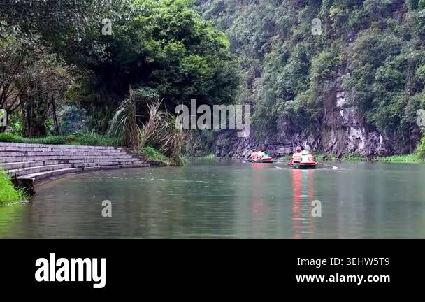Boats floating on calm water surrounded by lush green trees in a serene ...
