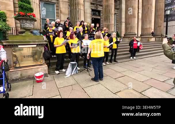 Chorus group singing outside in matching yellow shirts on building ...