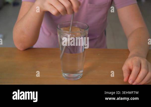 Close up woman stirring water with ice cube using metal stick with ...