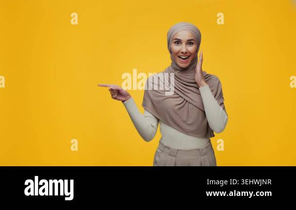 A woman wearing a headscarf expresses happiness and surprise. She is ...