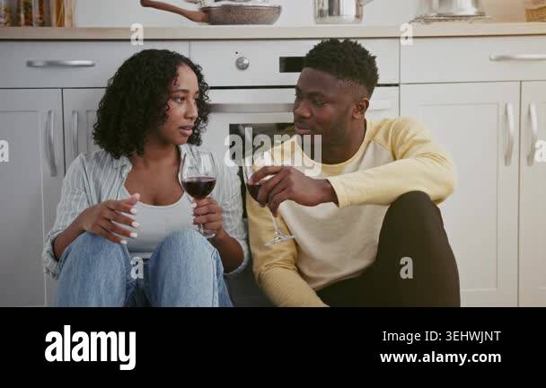 A Black man and an African American woman sit on the kitchen floor with ...