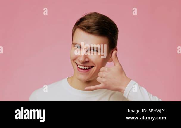 Young man with light skin is smiling and making a phone gesture with ...