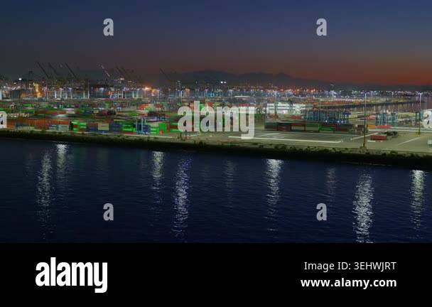 Illuminated commercial cargo shipping port at twilight features ...