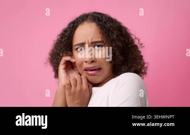 A young African American woman with curly hair displays a fearful ...
