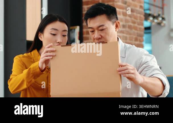 A man and a woman are looking at a box with concern. They are seated in ...