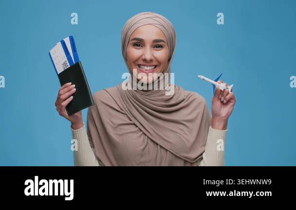 A woman smiles as she holds a passport and boarding passes in one hand ...