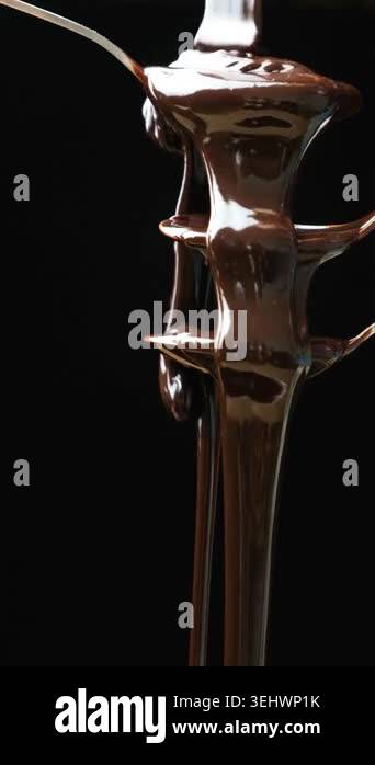 Slow motion of glossy chocolate sauce dripping on black background ...