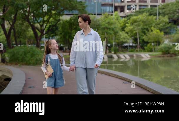 Portrait of cheerful mother with haircut and little girl student walk ...