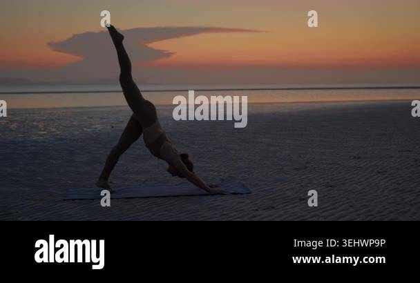 Silhouette of young sportswoman shows acrobatic yoga position on ocean ...