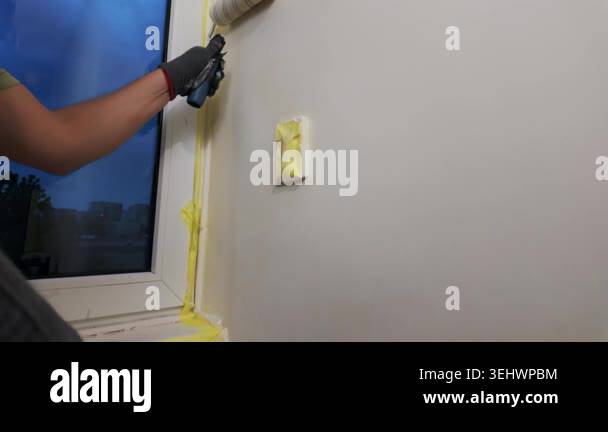 Person painting interior wall with roller near window at dusk Stock ...
