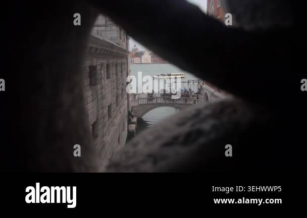 Misty Venice canal seen through stone bars, with a tour boat, bridge ...