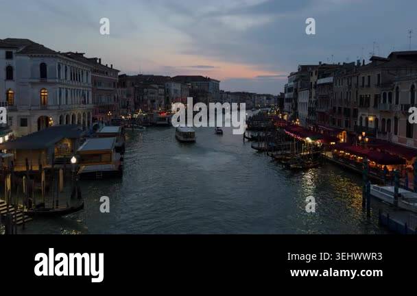 Slow-motion Venice canal at dusk with gondolas, warm terraces, historic ...
