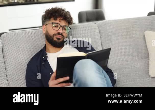 Man reading book and deeply thinking on sofa Stock Video Footage - Alamy