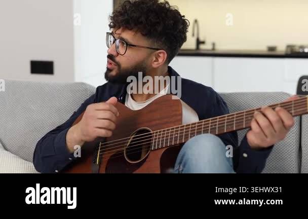 Man playing acoustic guitar on sofa at home Stock Video Footage - Alamy