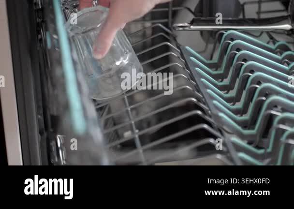 Person loading dirty dishes in dishwasher. Hand placing glasses in ...