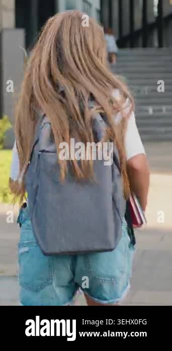 Rear view of Caucasian 11 year old girl with long hair and school bag ...