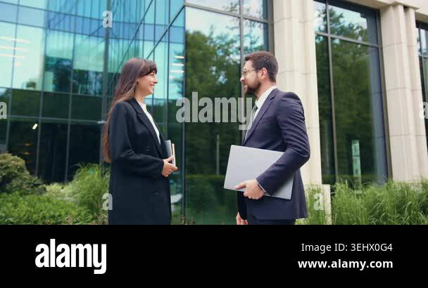 Businessman and businesswoman shaking hands in front of a modern office ...