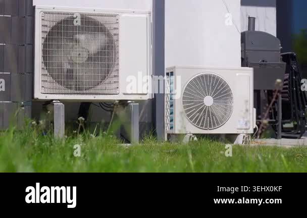 Heat pump outdoor unit runs with rotating fan beside an air conditioner ...