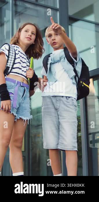 School students, teenage boy and girl standing near a building of ...