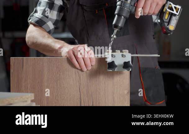Person using cordless drill with guide jig on wooden board in workshop ...