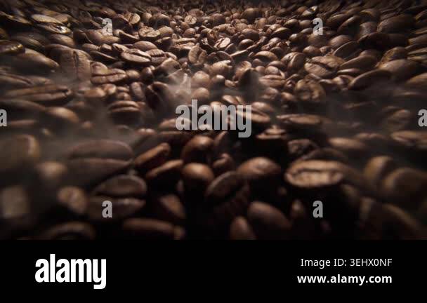 Wide angle sliding shot of roast coffee beans with gentle smoke on a ...