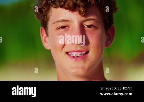 Portrait of a smiling teenage boy with braces, standing outdoors ...