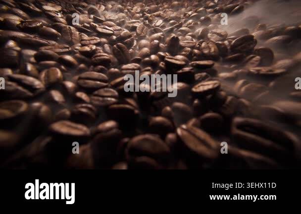 Wide angle sliding shot of roast coffee beans with gentle smoke on a ...