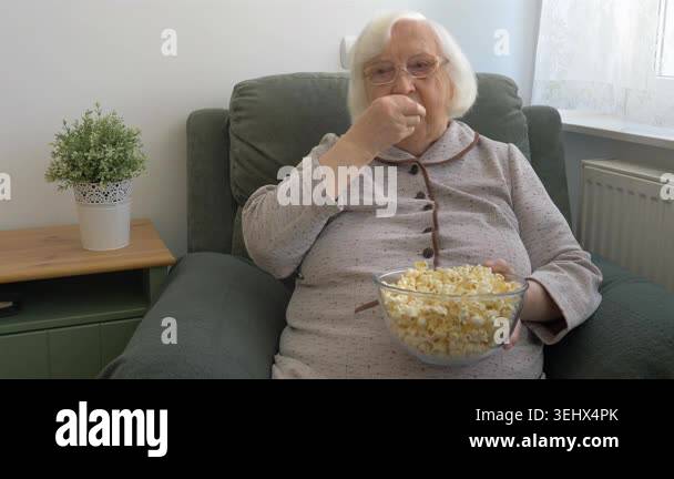 Old woman is eating popcorn while watching TV Stock Video Footage - Alamy