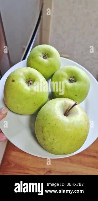 Vertical, close-up shot of a hand holding a white plate with four fresh ...
