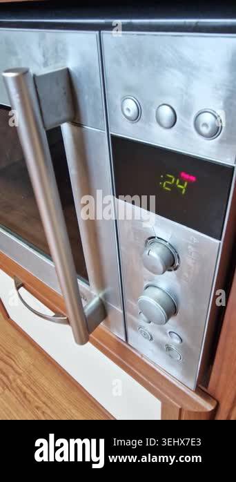 Close-up of a stainless steel microwave oven with a bright red digital ...