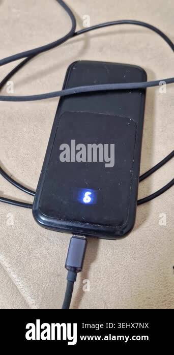 Vertical, overhead shot of a black portable power bank showing a blue ...