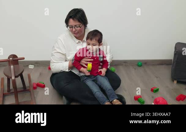Loving mother sitting on the floor with her young son on her lap ...