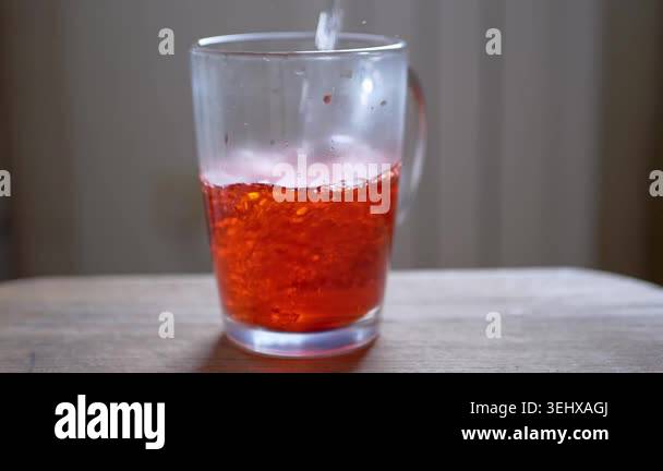 Bright red liquid, possibly fruit juice or tea, is poured into a ...