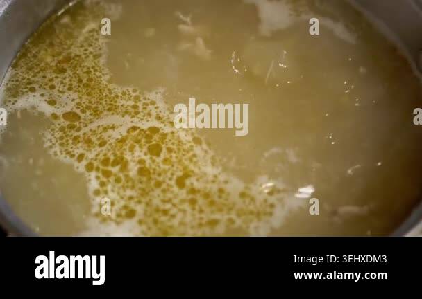 Boiling chicken broth simmers inside a stainless steel pot with oil ...