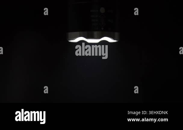 A bright LED flashlight beam shines downwards against a black ...