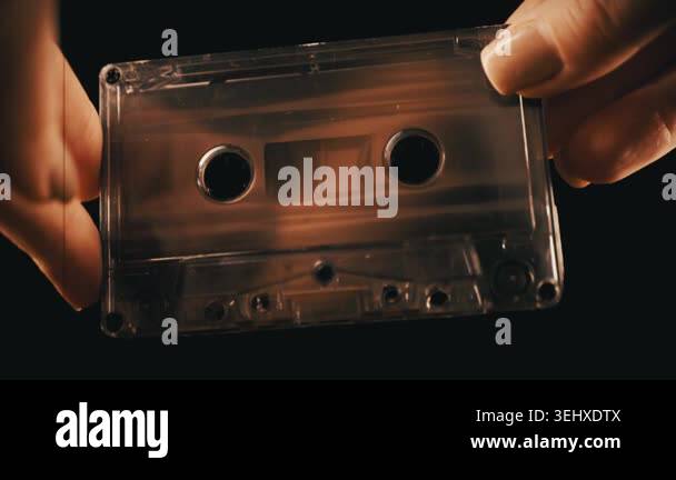 Female hands hold a transparent vintage audio cassette tape against a ...