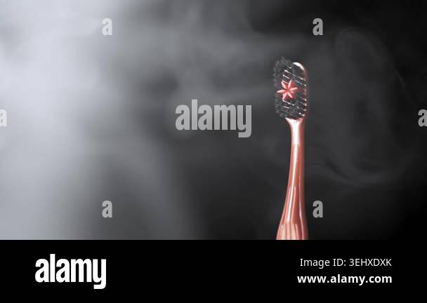A close-up view of a rose gold toothbrush with dark bristles standing ...