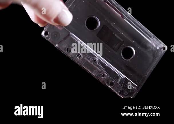 Female hands hold and turn a transparent audio cassette tape against a ...