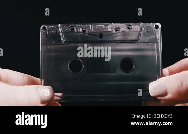 Female hands hold a transparent blank audio cassette tape against a ...