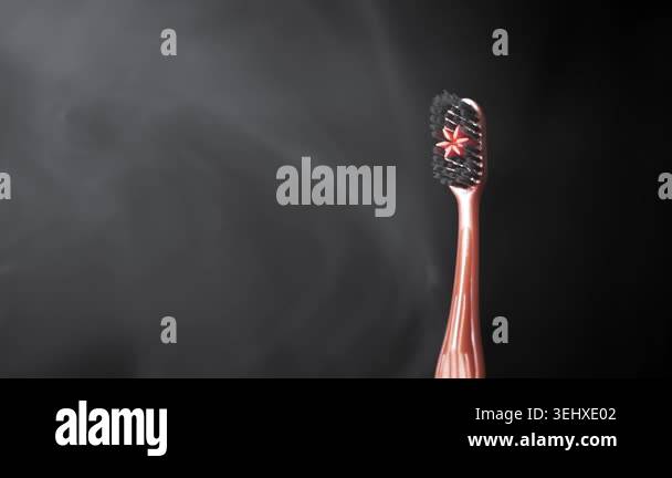 A close-up of a rose gold toothbrush with black bristles standing ...