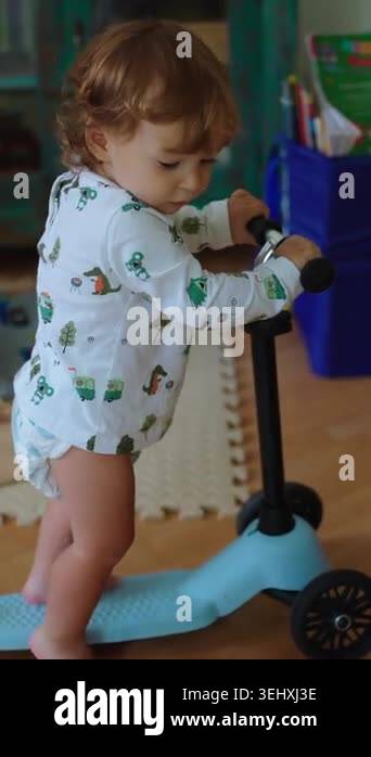 Young child rides small scooter across home interior during calm family ...