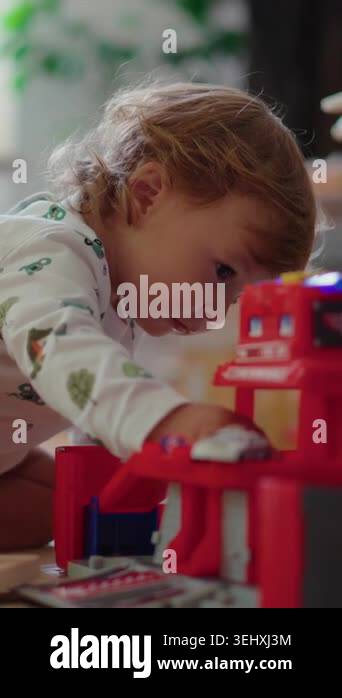 Young child explores toy emergency vehicle set at home during calm ...