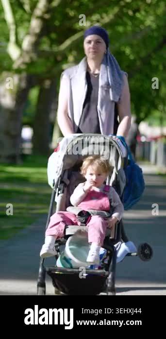 Mother undergoing chemotherapy walks with child in stroller through ...