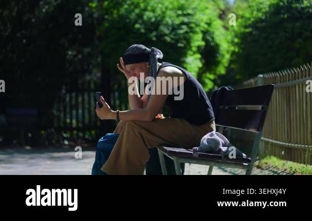 Female cancer patient sits outdoors in sunlight while speaking on a ...