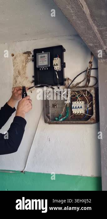 Medium shot of an electrician's hands stripping an electrical cable ...