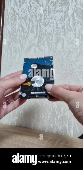Vertical, close-up shot of two hands holding a laptop hard drive ...