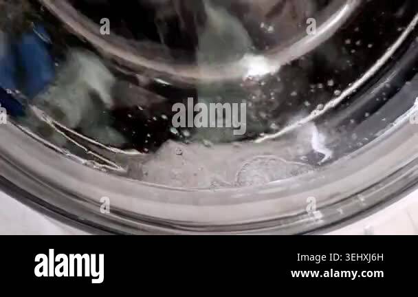 Close-up view through a washing machine glass door. The drum rotates ...